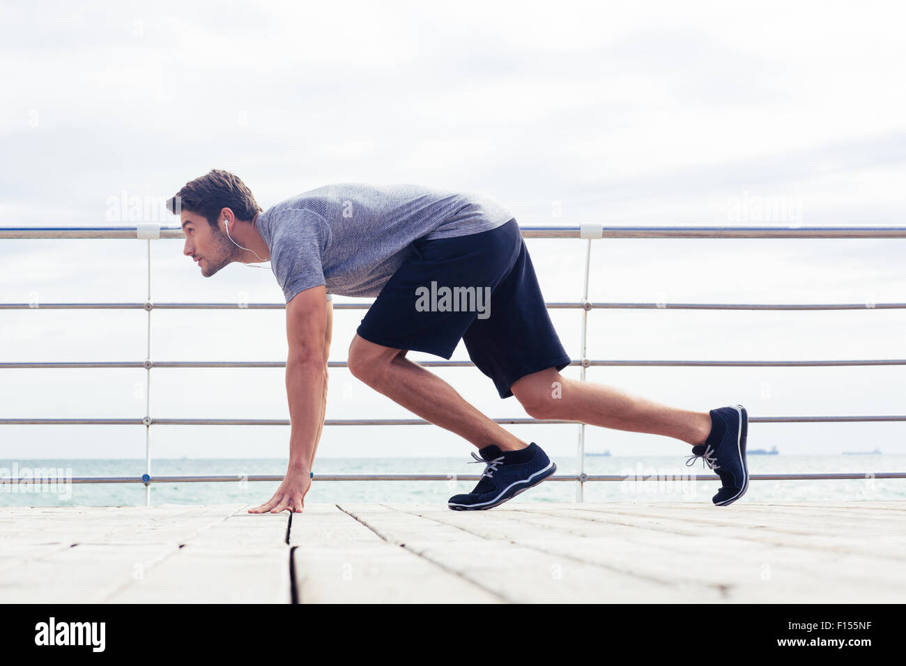 Portrait of a sports man in start position outdoors. Reading for run ...