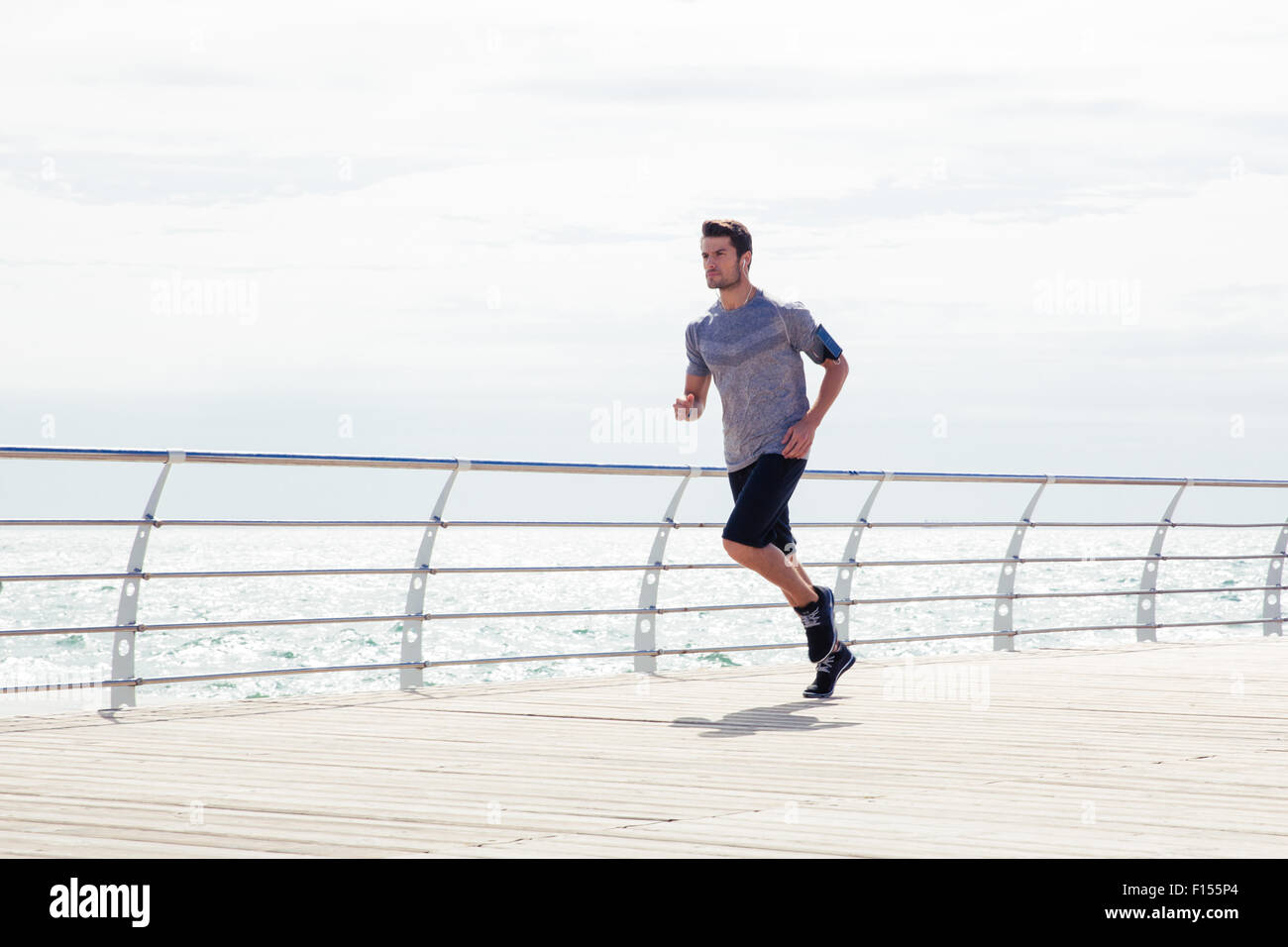 Full length portrait of a handsome sports man running outdoors near sea ...