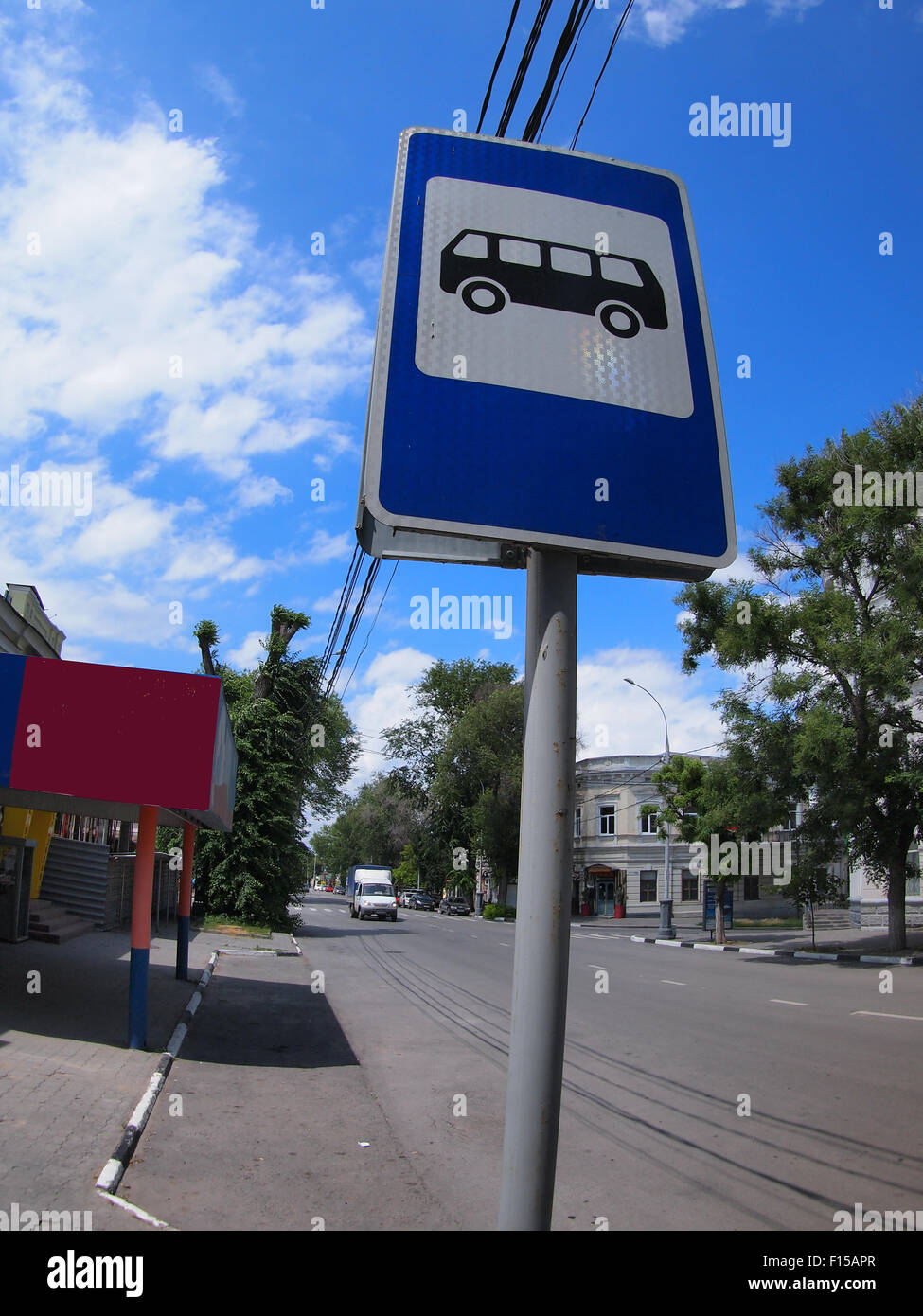 Road sign with a picture of a bus stop on a city street with wide angle ...
