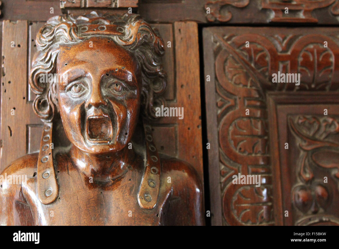 Medieval wood carving on cupboard door, of a man's face shouting ...