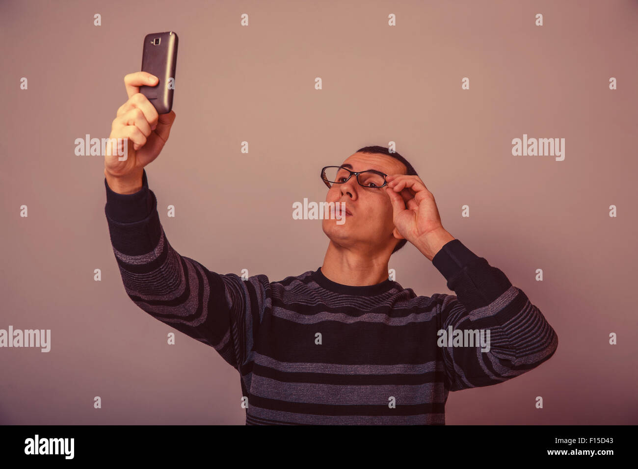 European-looking man of 30 years in glasses looks at the phone r Stock ...