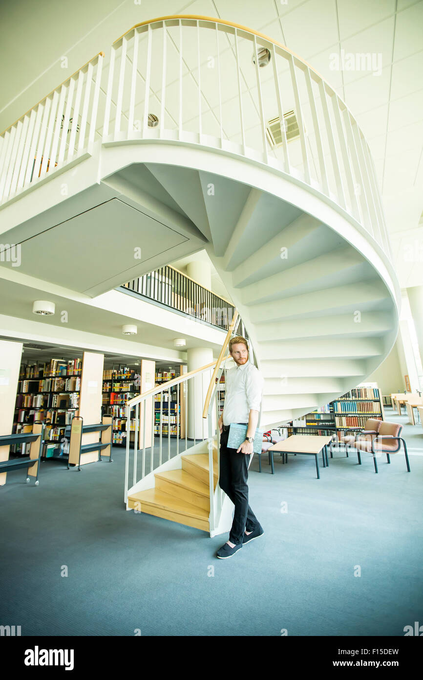 Young man on the stairs at library Stock Photo - Alamy