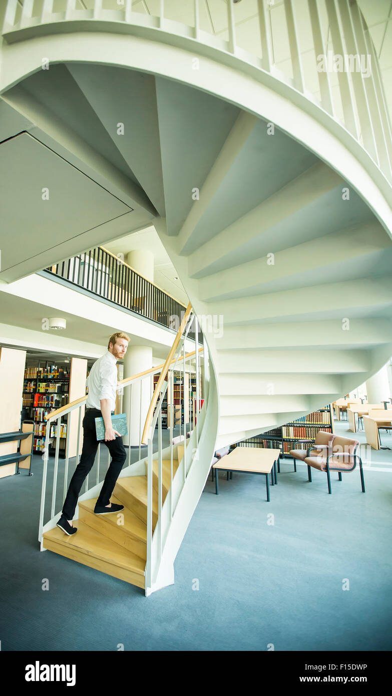 Young man on the stairs at library Stock Photo - Alamy