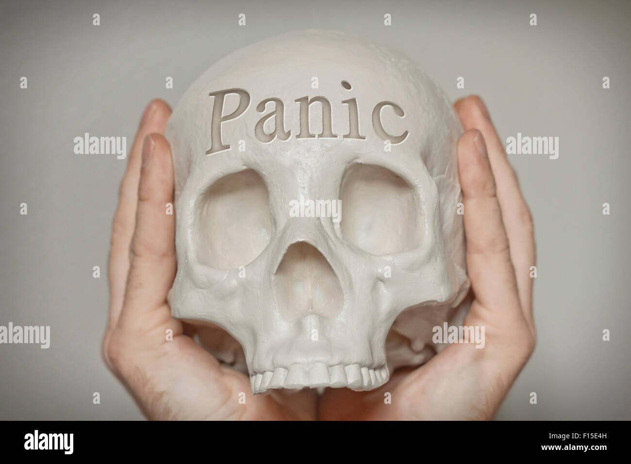 Engraved word panic on skull forehead with hands clasping to emphasize ...
