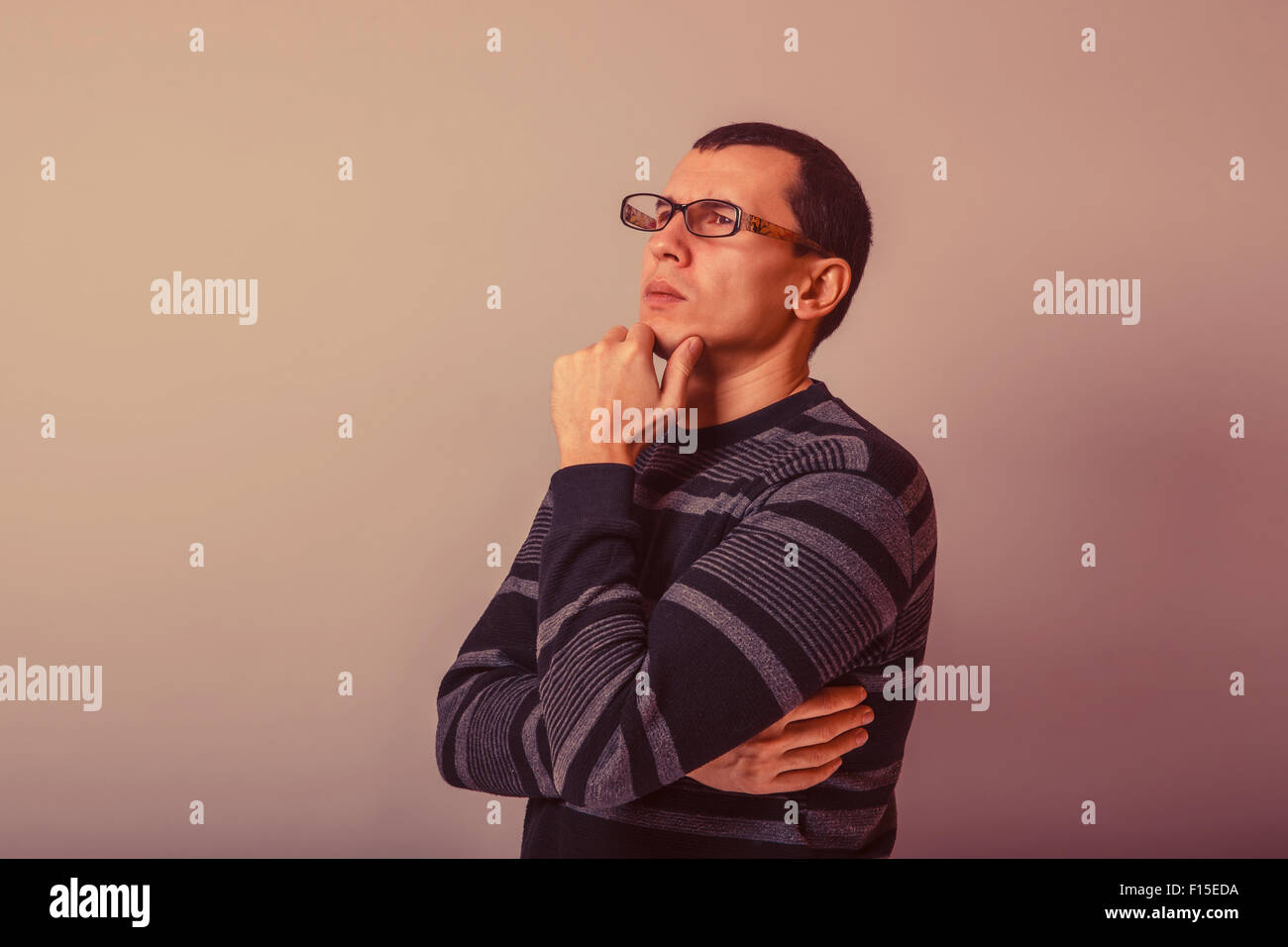 male of European appearance brunet holding hand on chin thinking Stock ...