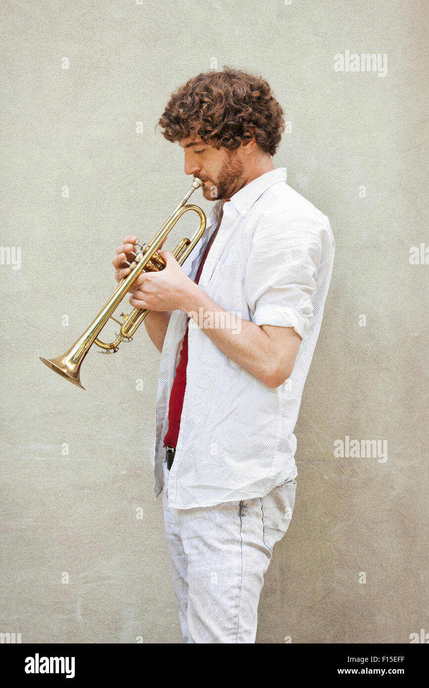 Curly haired man plays jazz trumpet outside Stock Photo - Alamy