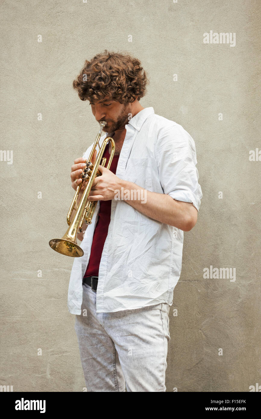 Curly haired man plays jazz trumpet outside Stock Photo - Alamy