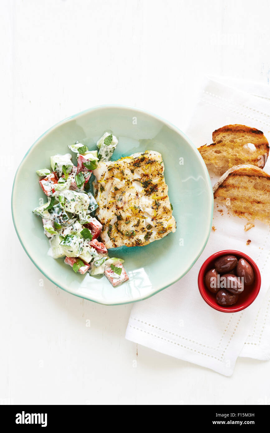 Lemon Cod with Greek Salad on a green plate, with Bread and Olives in ...