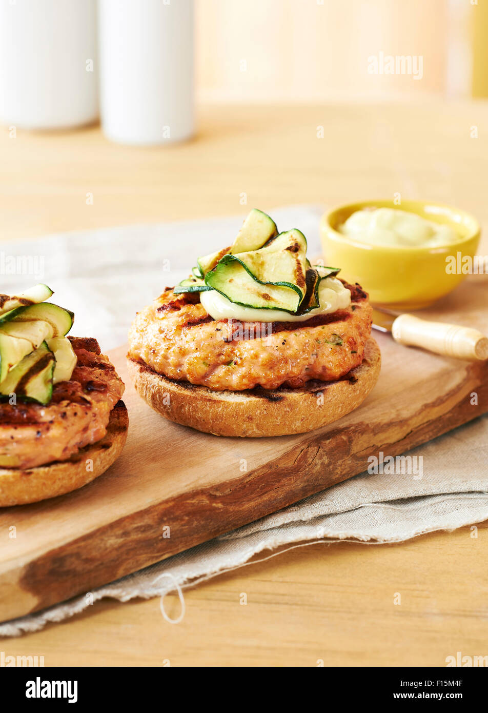Grilled, open-faced salmon burgers with aioli and zucchini on wooden ...