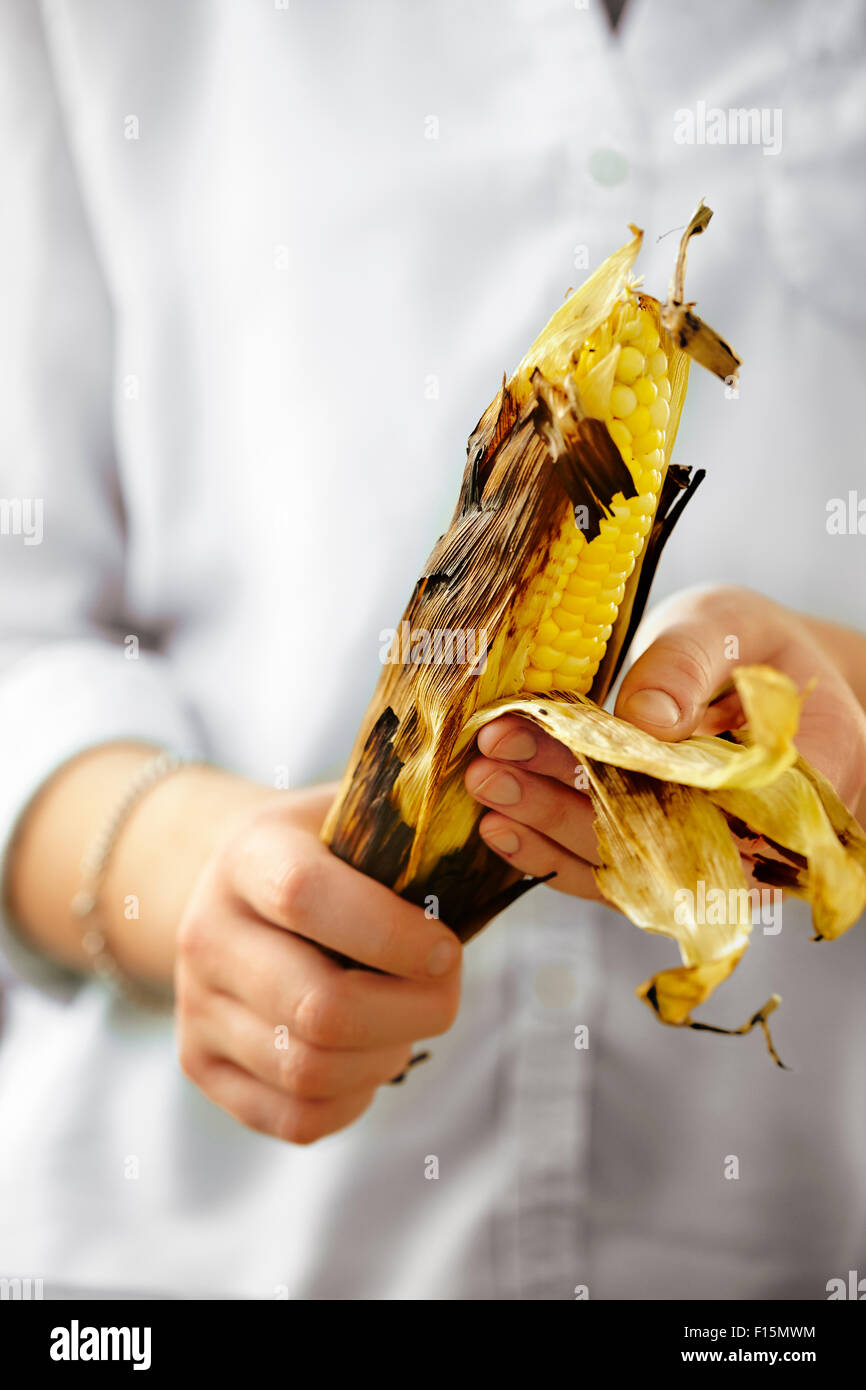 Close-up of Woman's Hands holding Roasted Corn Cob with Blackened Husk ...