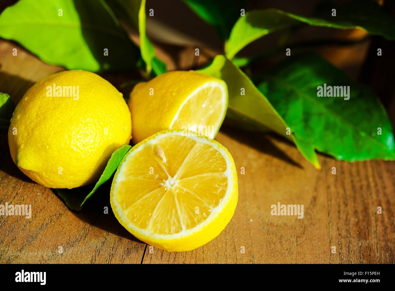 Fresh Sliced Lemon and Lemon Tree Leaves on Wooden Table Stock Photo ...