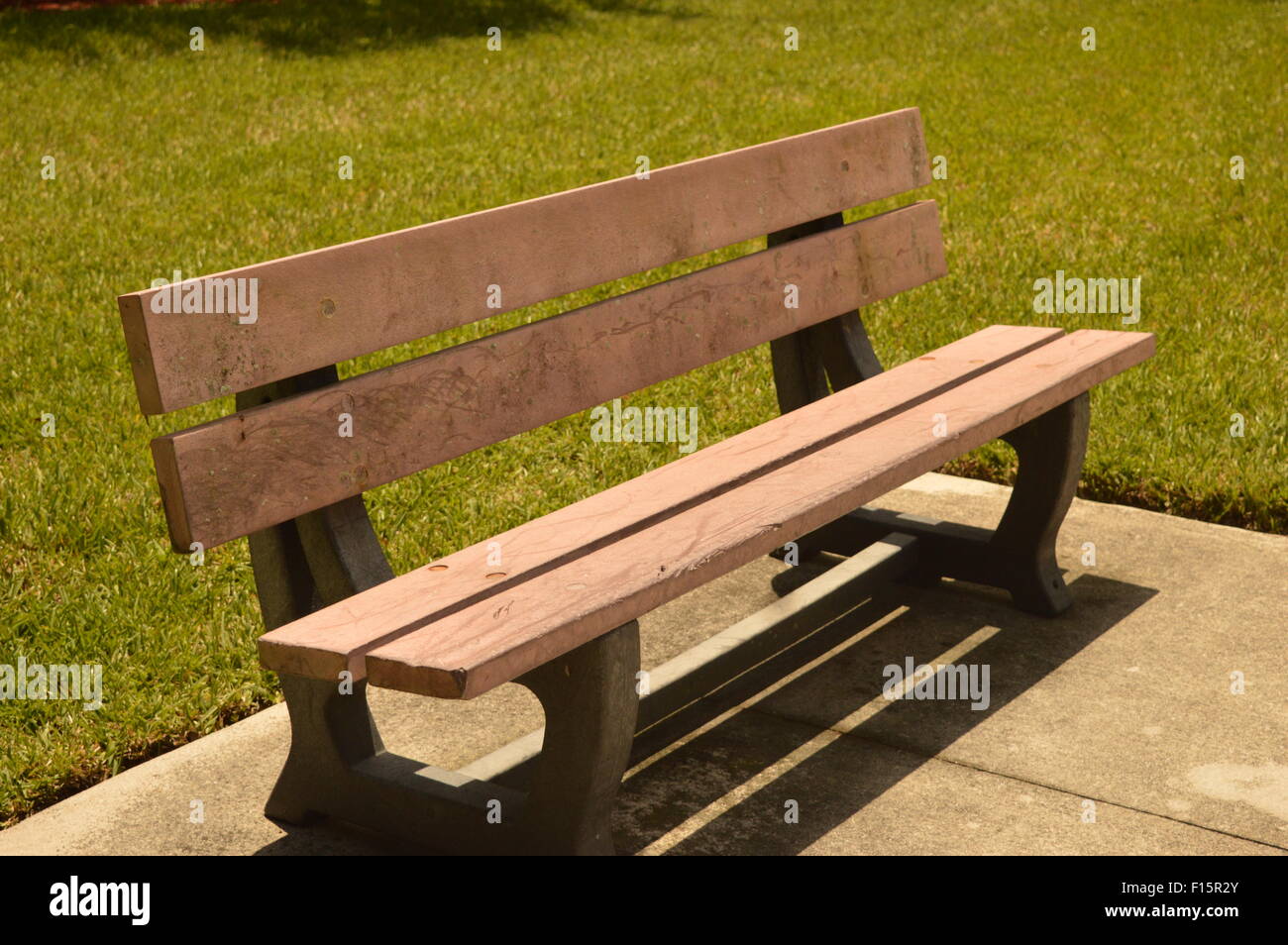 Brown bench at an angle in a park Stock Photo - Alamy