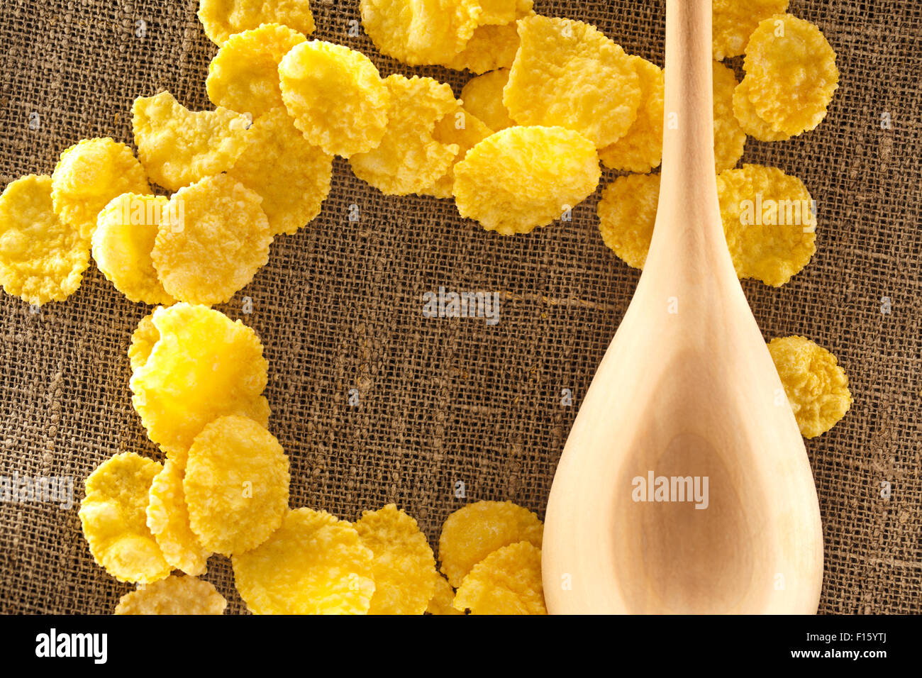 Wooden spoon and corn flakes on sack background closeup Stock Photo - Alamy