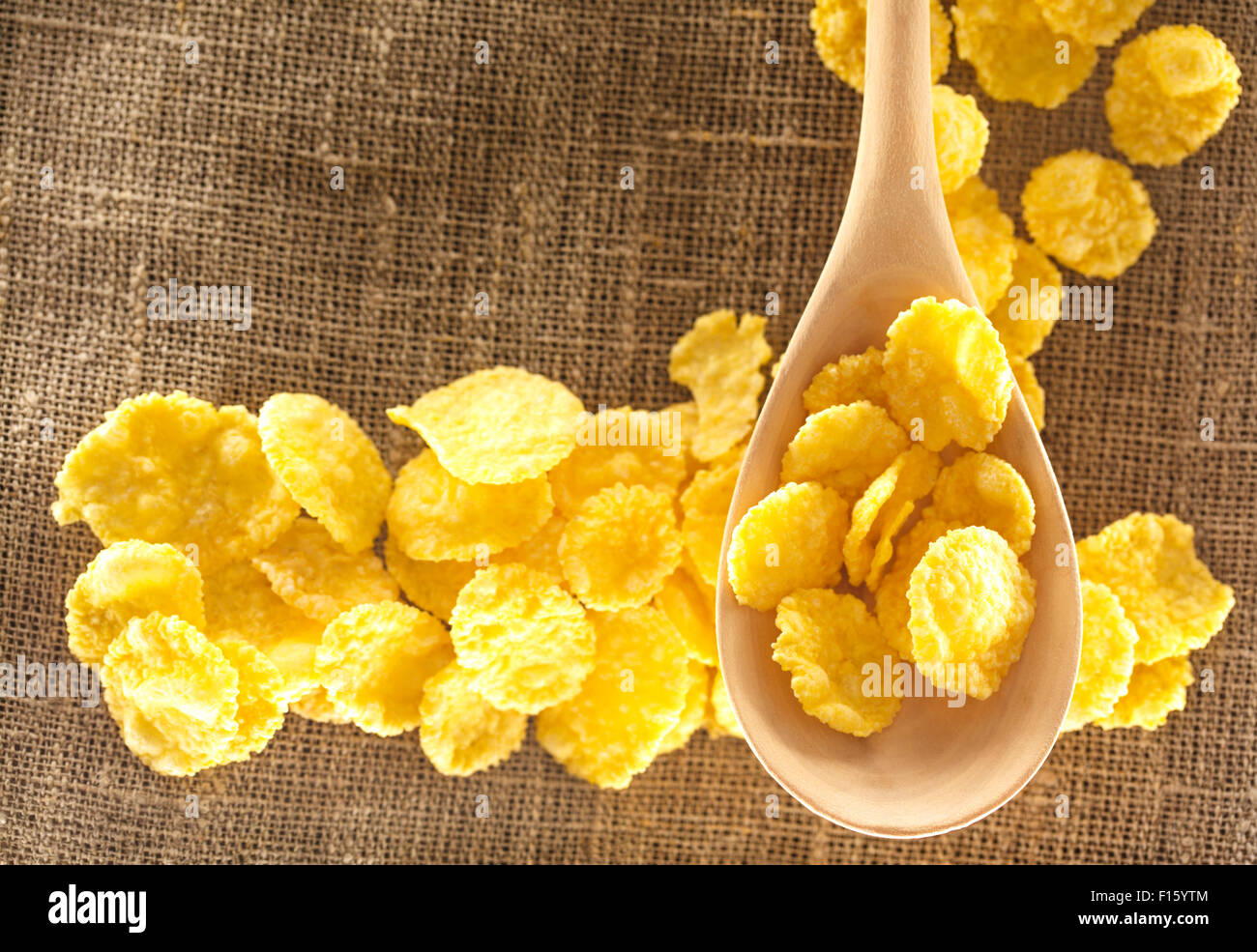 Wooden spoon and corn flakes on sack background closeup Stock Photo - Alamy