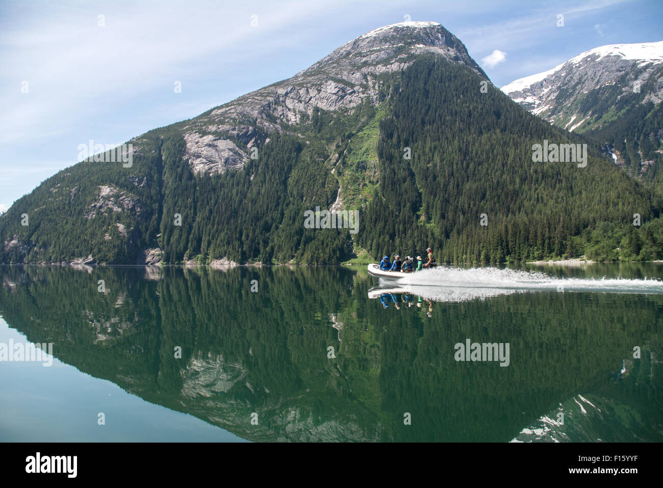 A wilderness guide and tourists travel up a remote lake by zodiac in ...