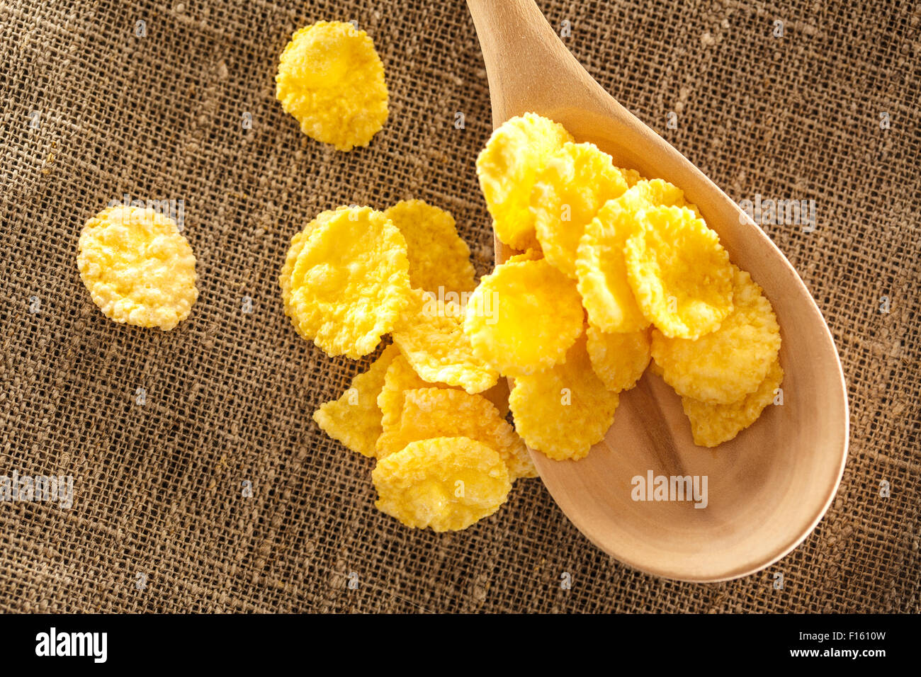 Wooden spoon and corn flakes on sack background closeup Stock Photo - Alamy