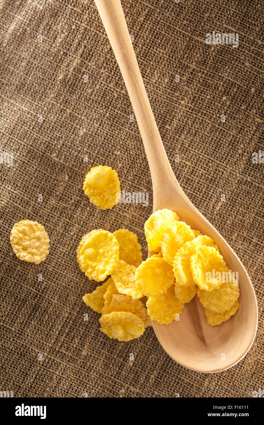 Wooden spoon and corn flakes on sack background closeup Stock Photo - Alamy
