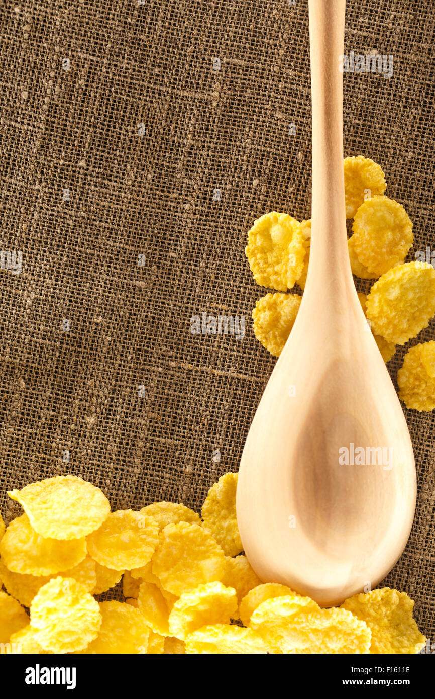 Wooden spoon and corn flakes on sack background closeup Stock Photo - Alamy