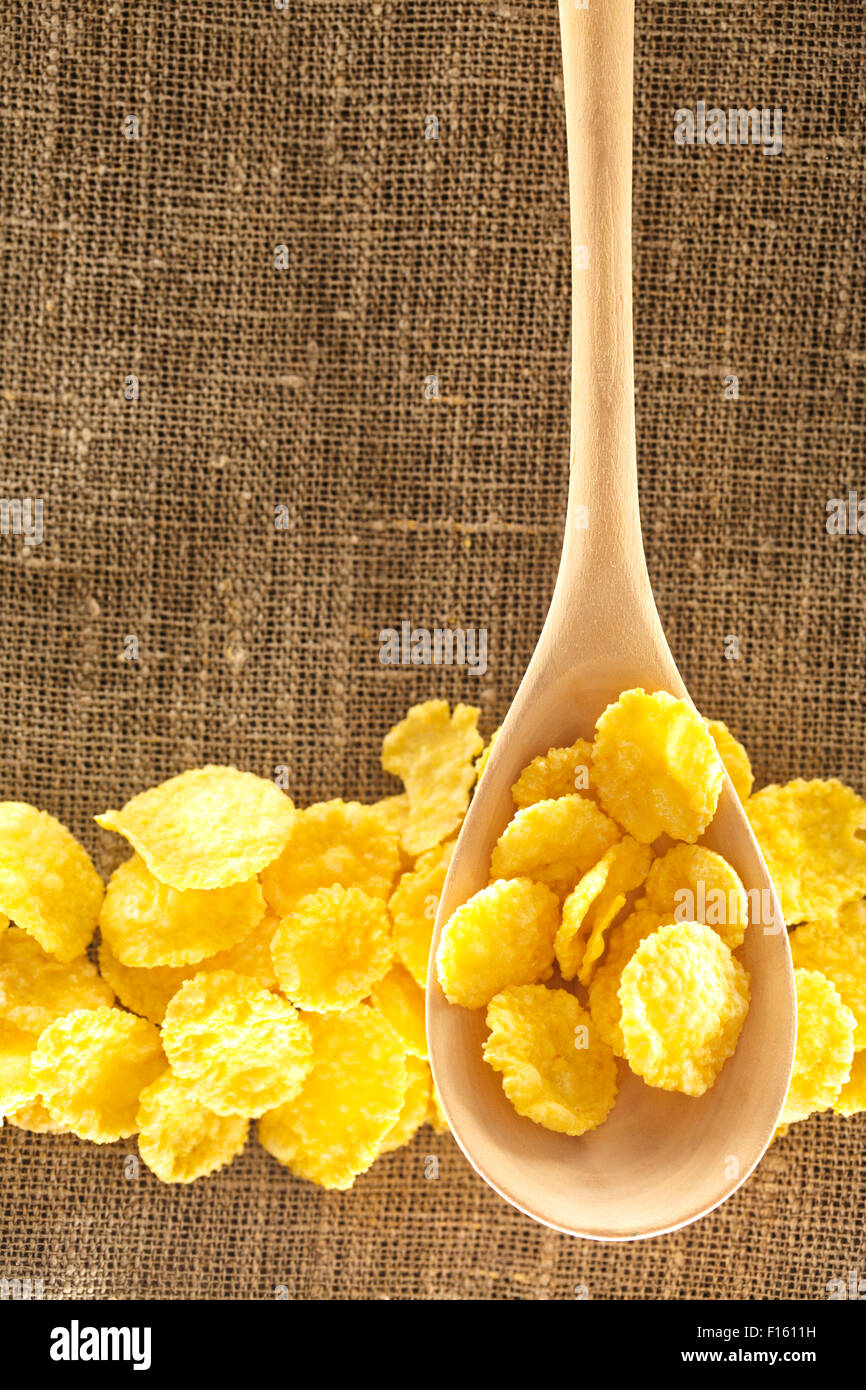 Wooden spoon and corn flakes on sack background closeup Stock Photo - Alamy