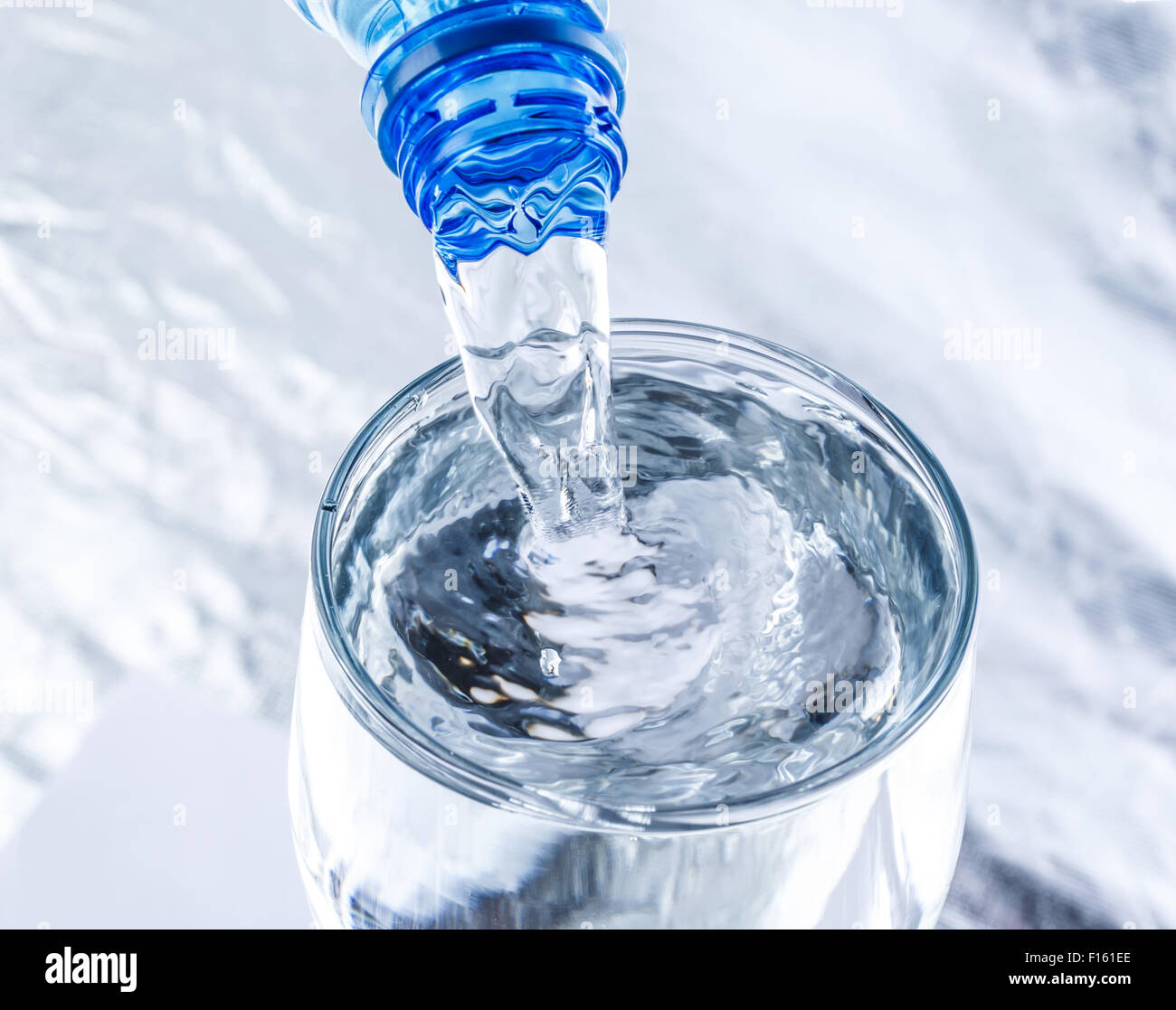Pouring water from bottle into glass in blue toning Stock Photo - Alamy