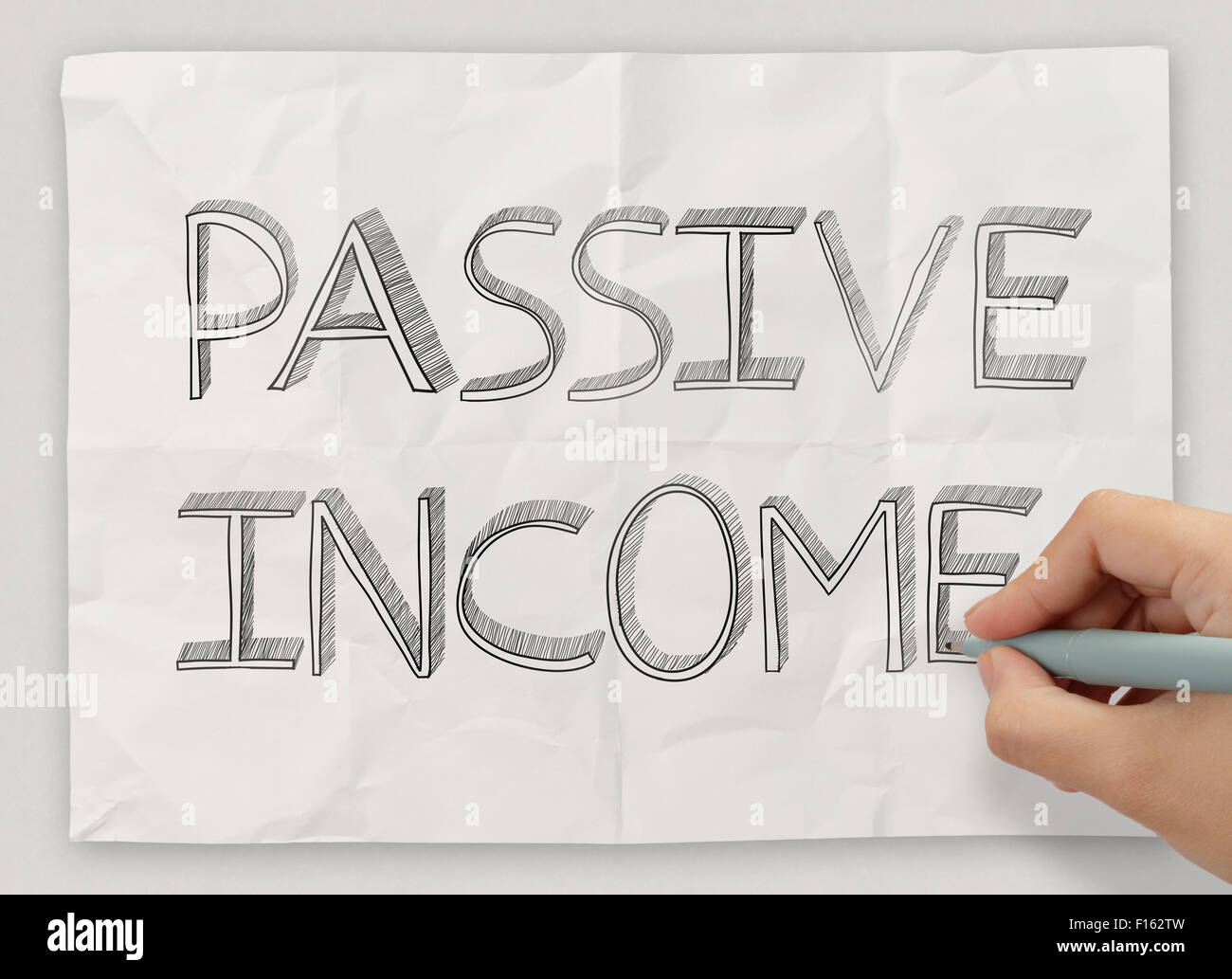 close up of hand drawing passive income on crumpled paper background as ...