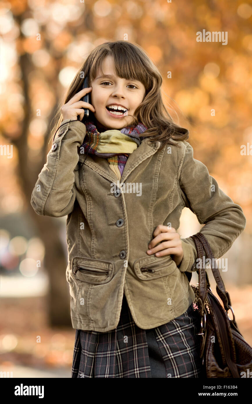 vertical photo, stylish beautiful little girl hold mobile phone and ...