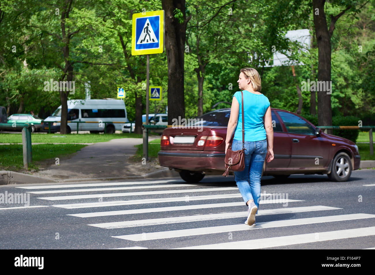 Woman crossing the street at a pedestrian crossing Stock Photo - Alamy