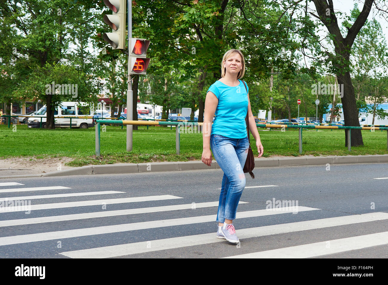Woman crossing the street is dangerous at a red light Stock Photo - Alamy