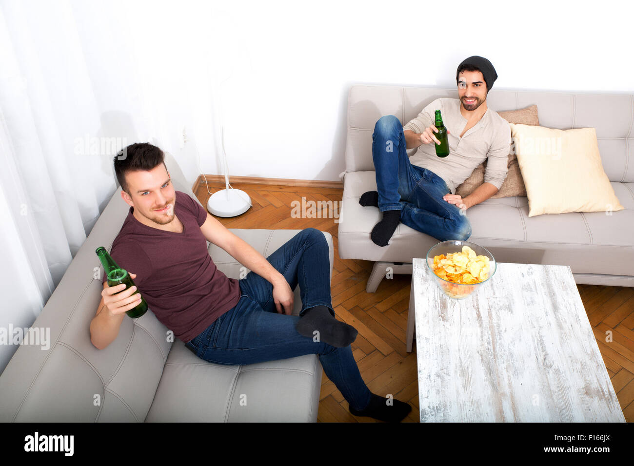 Two young men drinking beer at home Stock Photo - Alamy