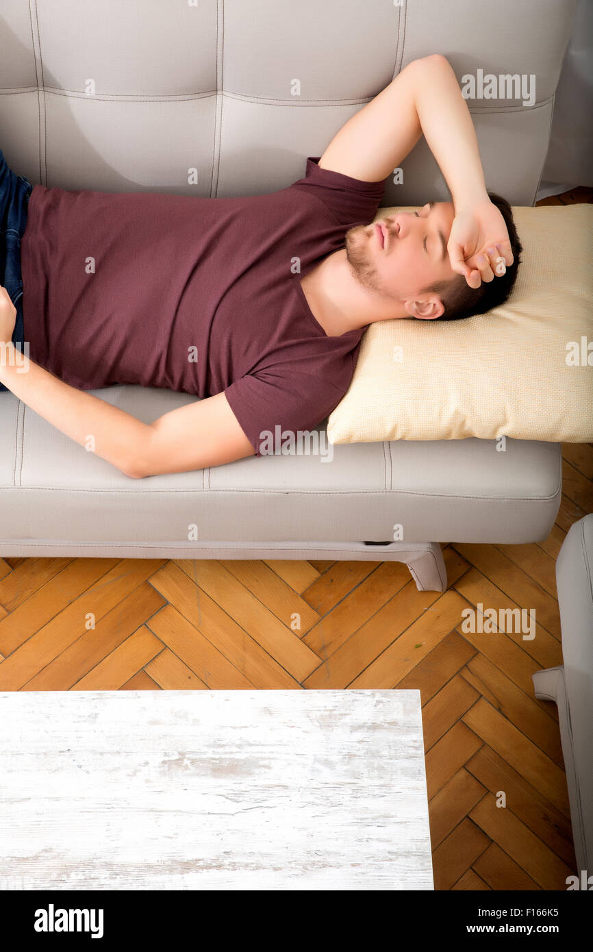 Young man laying on the sofa at home Stock Photo - Alamy