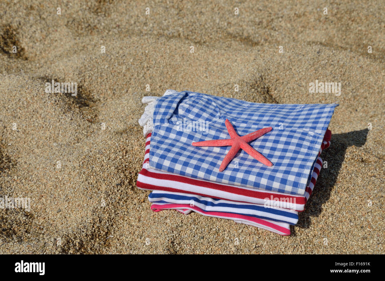 Navy look summer clothes on a sandy beach, with sea star on it Stock ...
