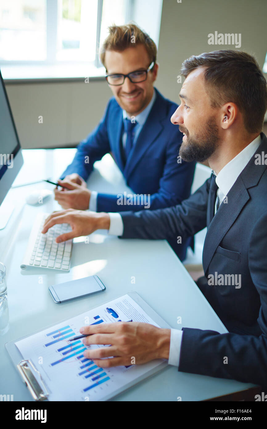 Confident businessmen sitting in front of computer in office Stock ...