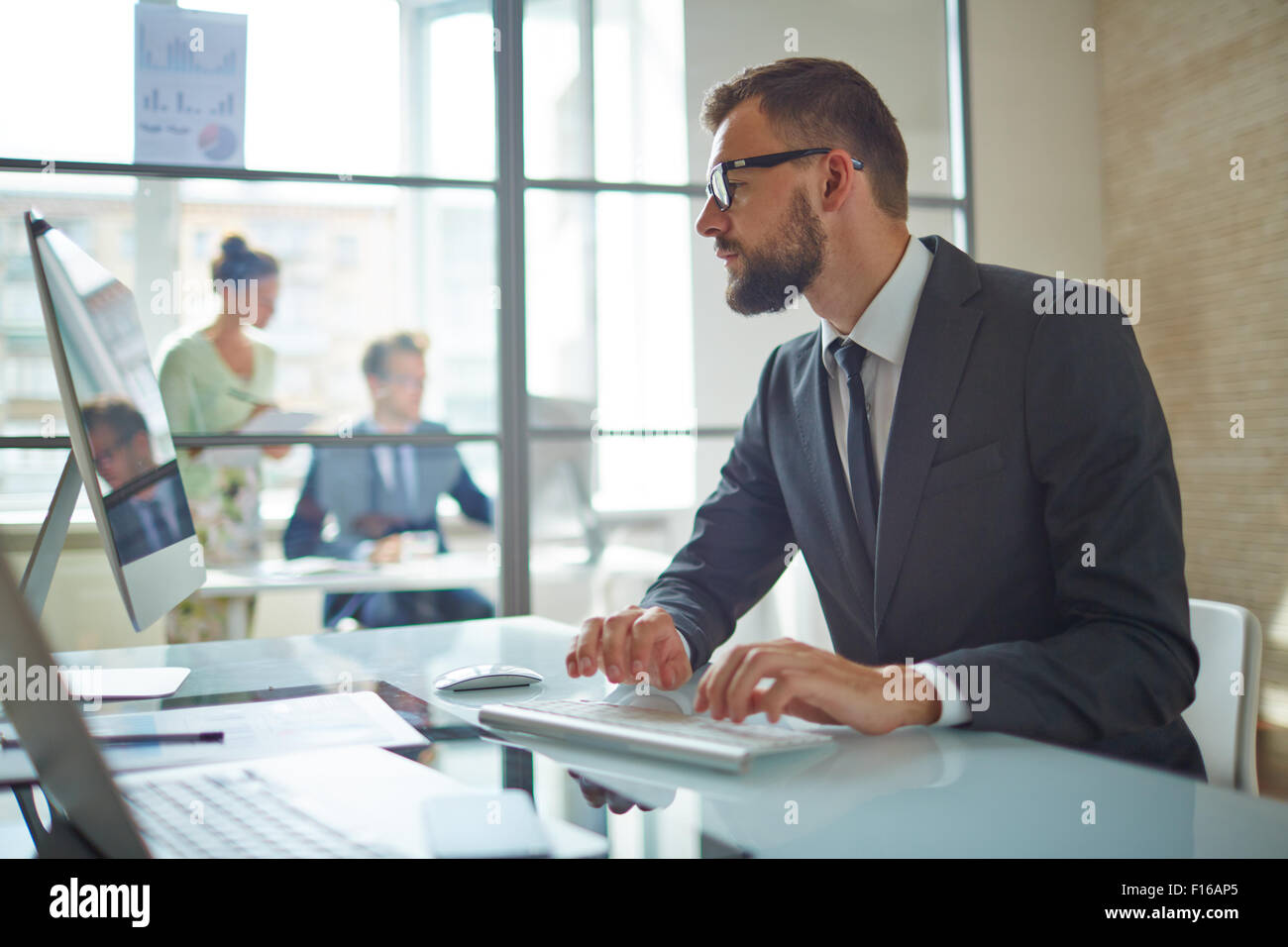 Young employee looking at computer monitor Stock Photo - Alamy