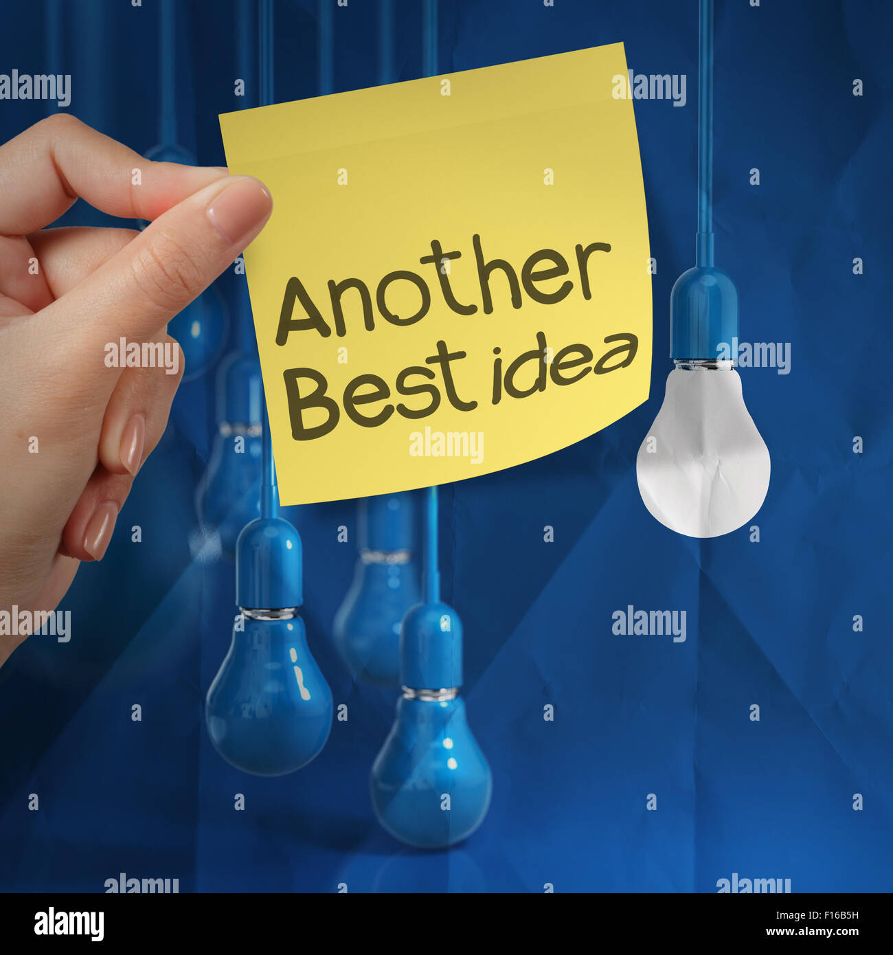 hand holding sticky note with another idea light bulb on crumpled paper ...