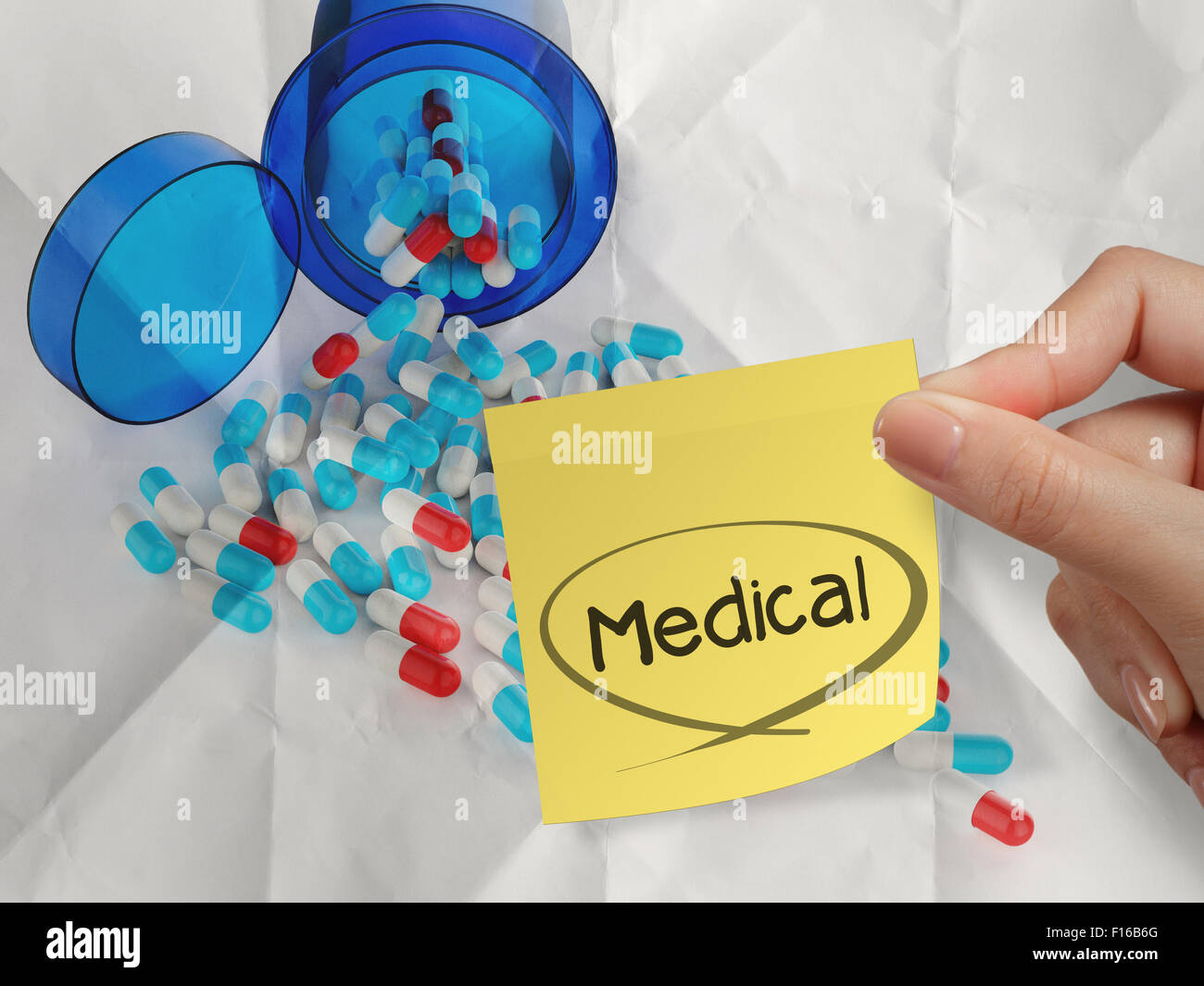 hand holding medical sticky note on Pills spilling out of pill bottle ...