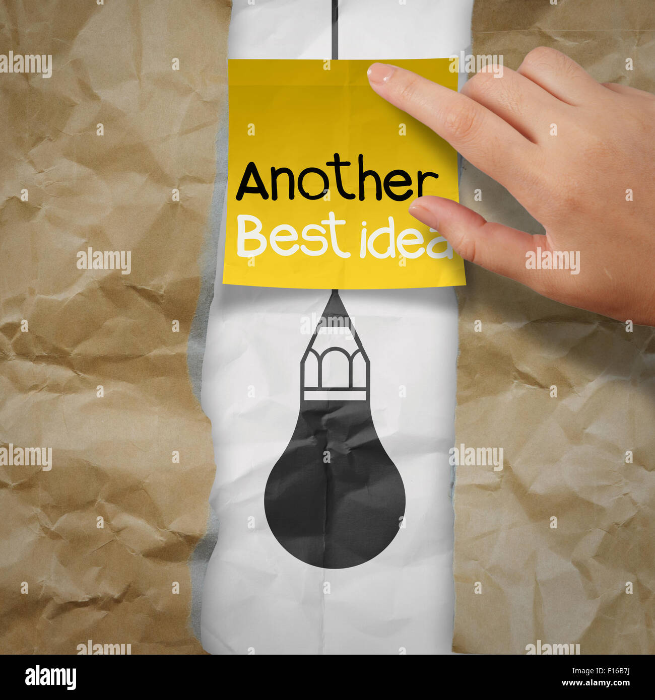 hand holding sticky note with another idea light bulb on crumpled paper ...