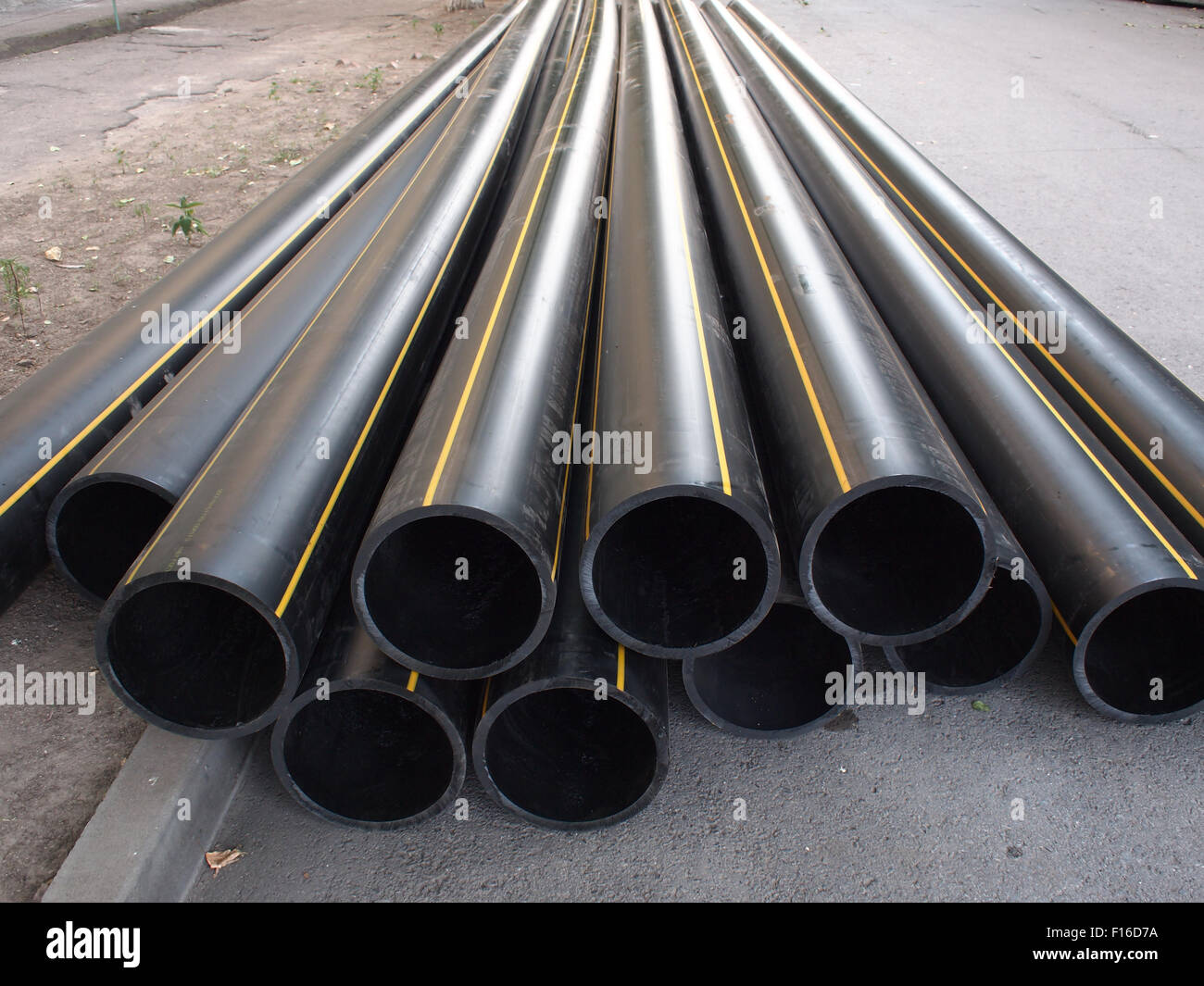 Black PVC pipes lie on the street on the pavement for the repair and ...