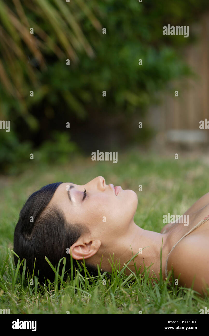 Young woman lying on back in grass, Profile Stock Photo - Alamy