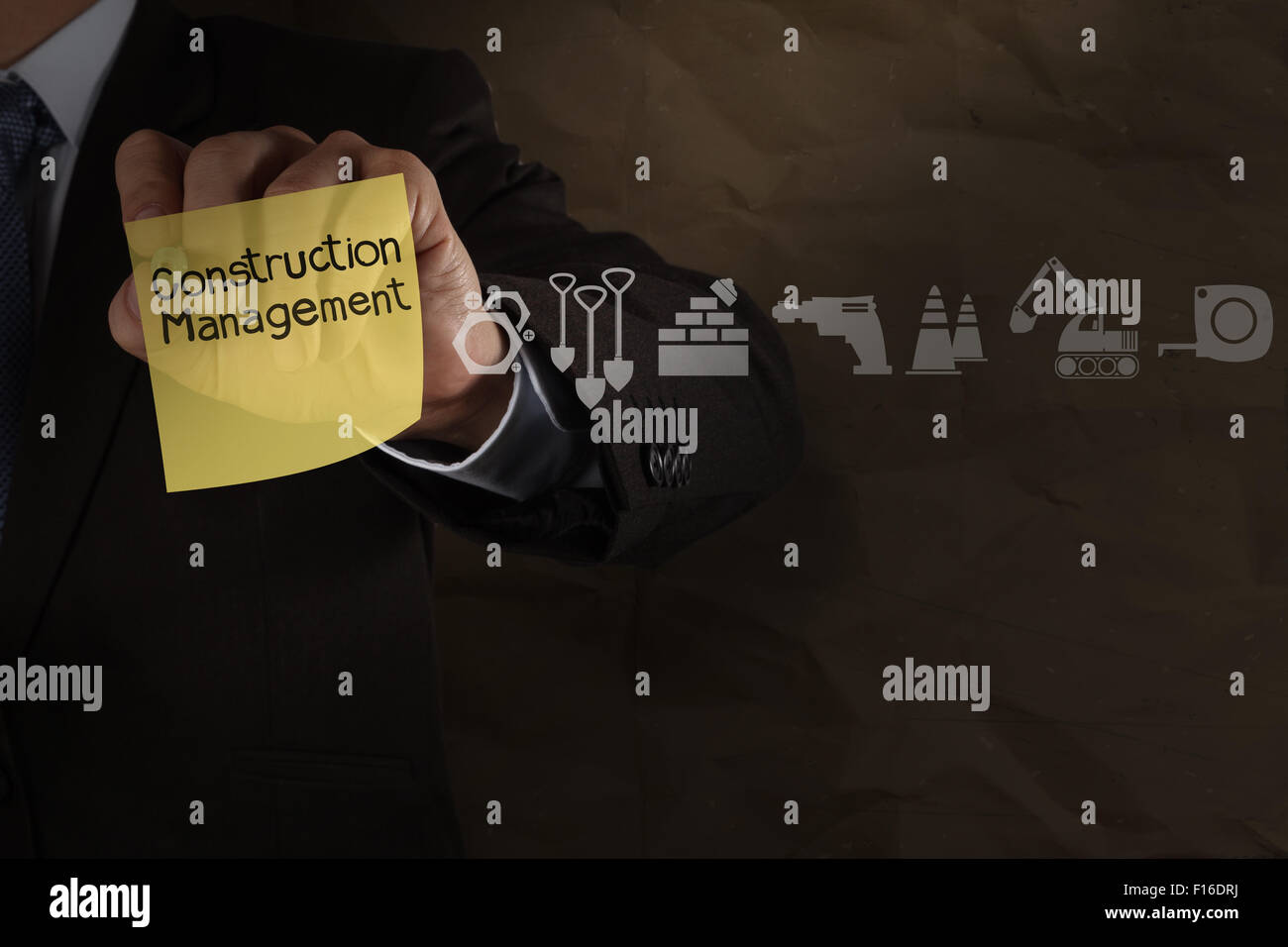 businessman hand point construction management on sticky note and icons ...