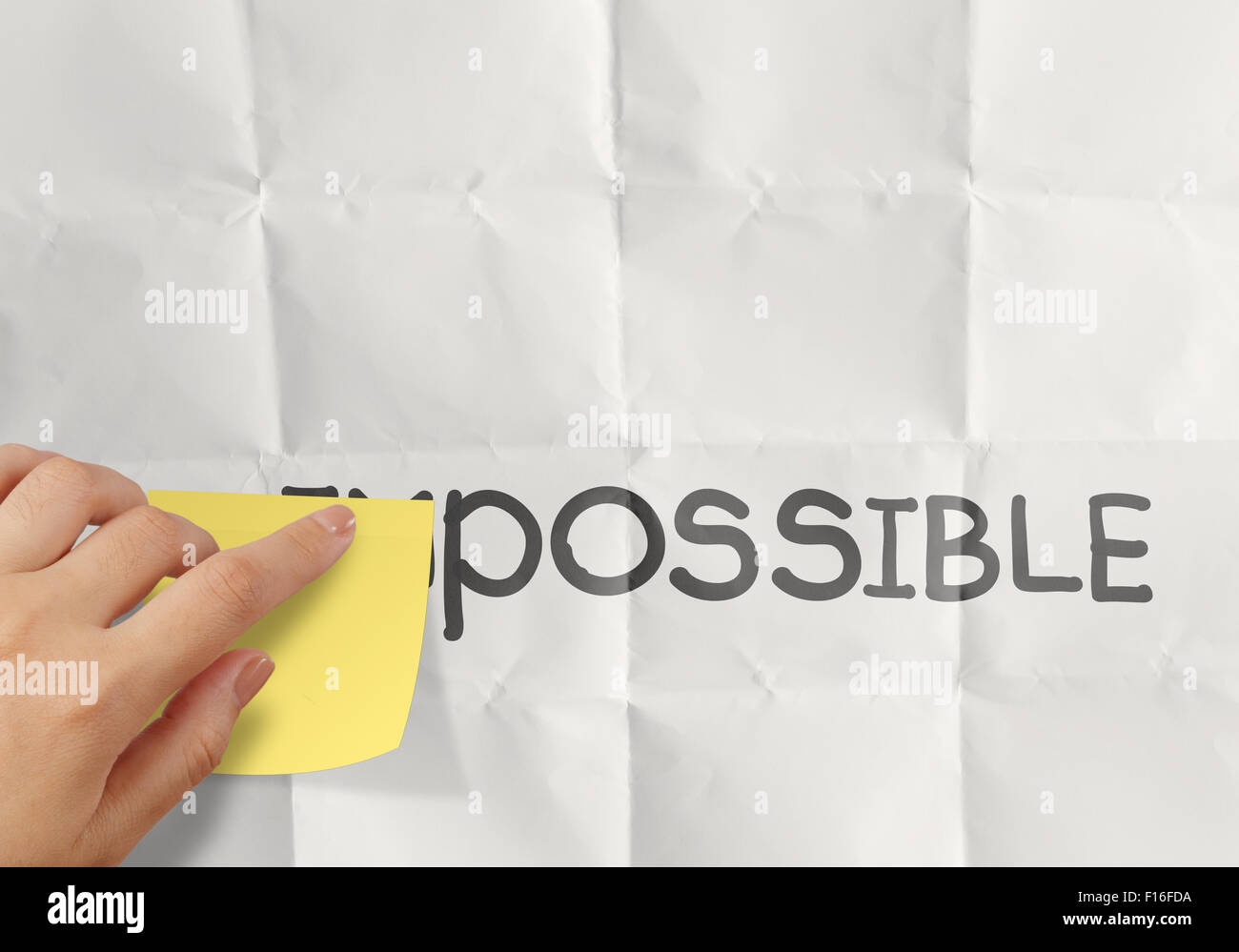 hand holding sticky note over word impossible transformed into possible ...