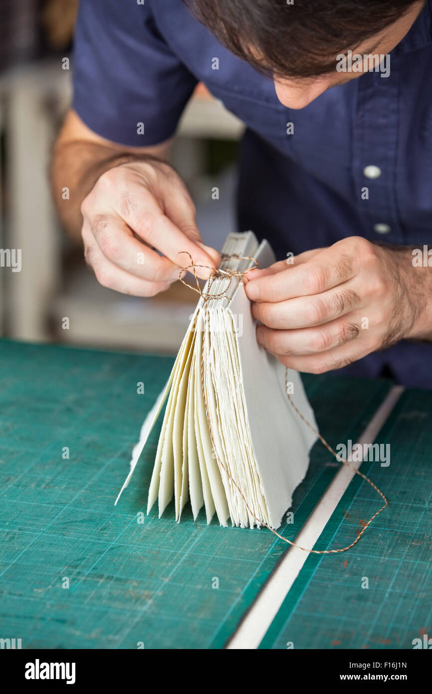 Mid Adult Man Binding Pages At Table Stock Photo - Alamy