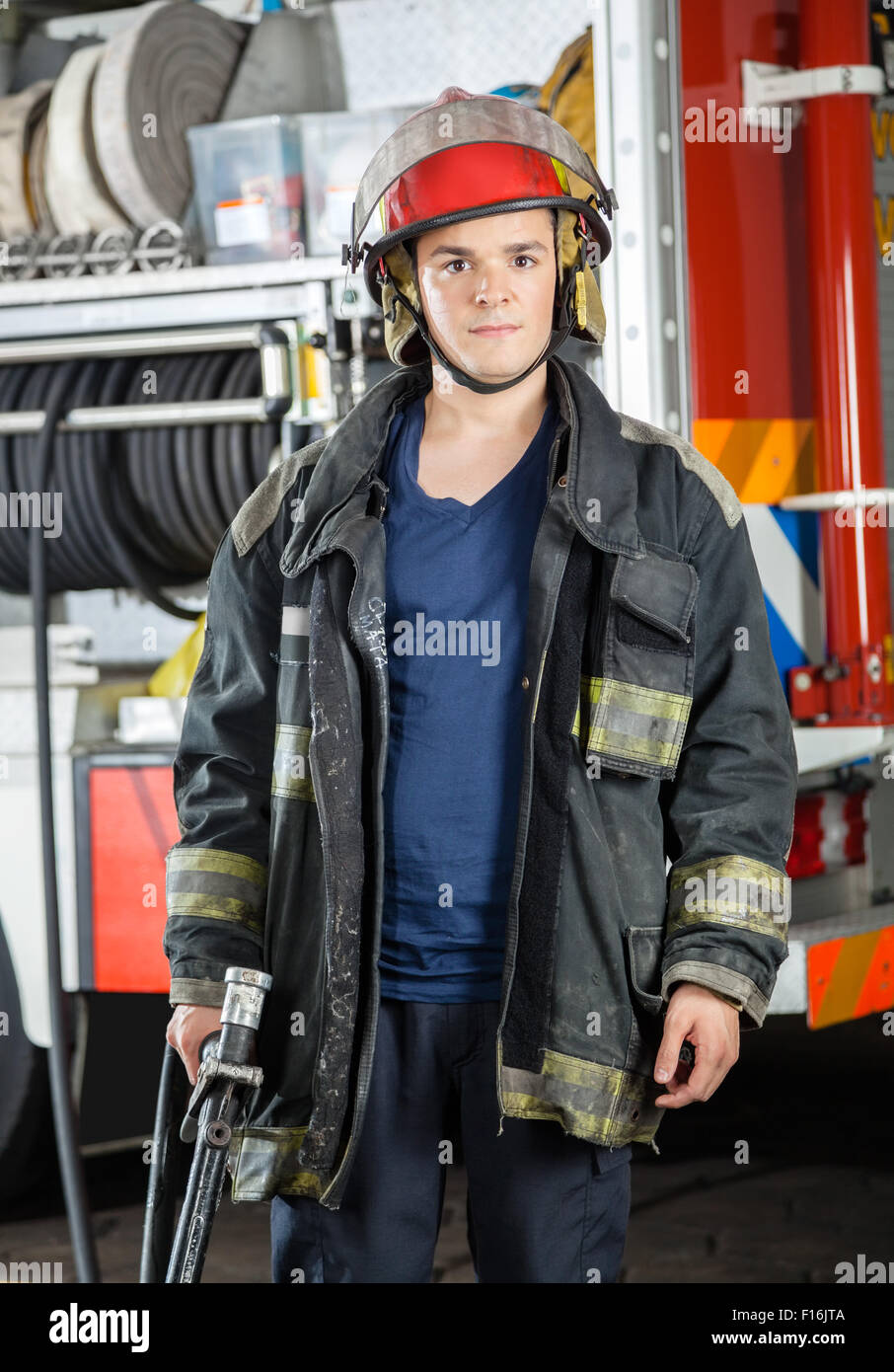 Confident Firefighter Holding Hose At Fire Station Stock Photo - Alamy