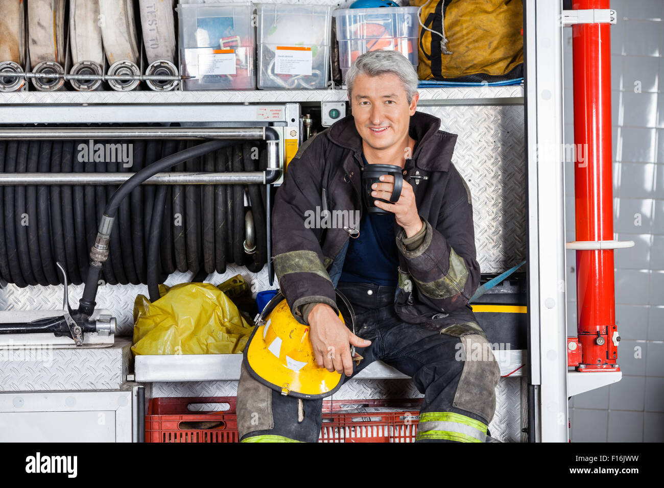 Smiling Fireman Sitting In Truck At Fire Station Stock Photo - Alamy