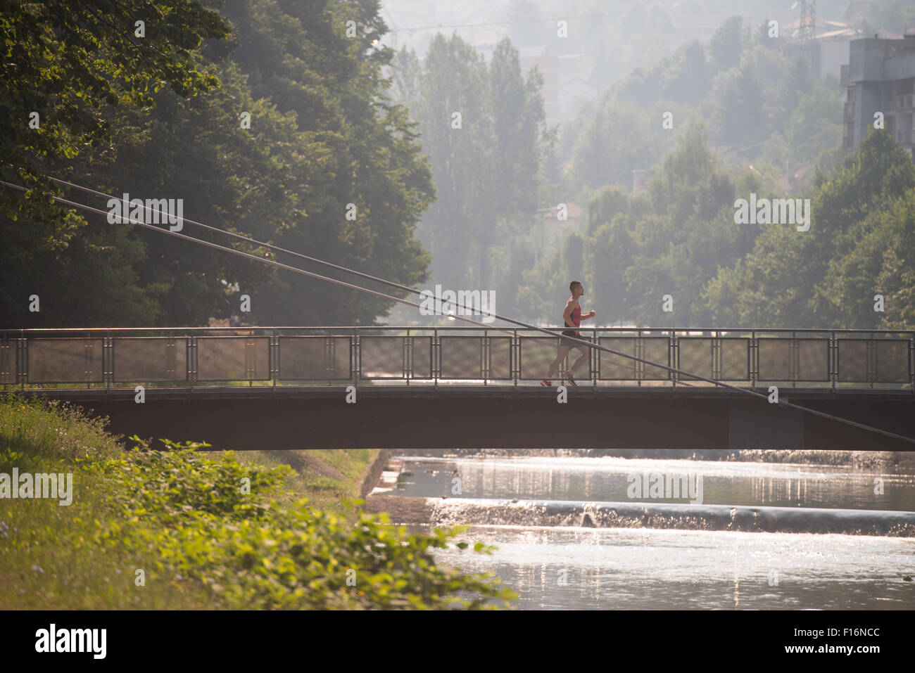 Young Man Running On Bridge In Wooded Forest Area - Training And ...