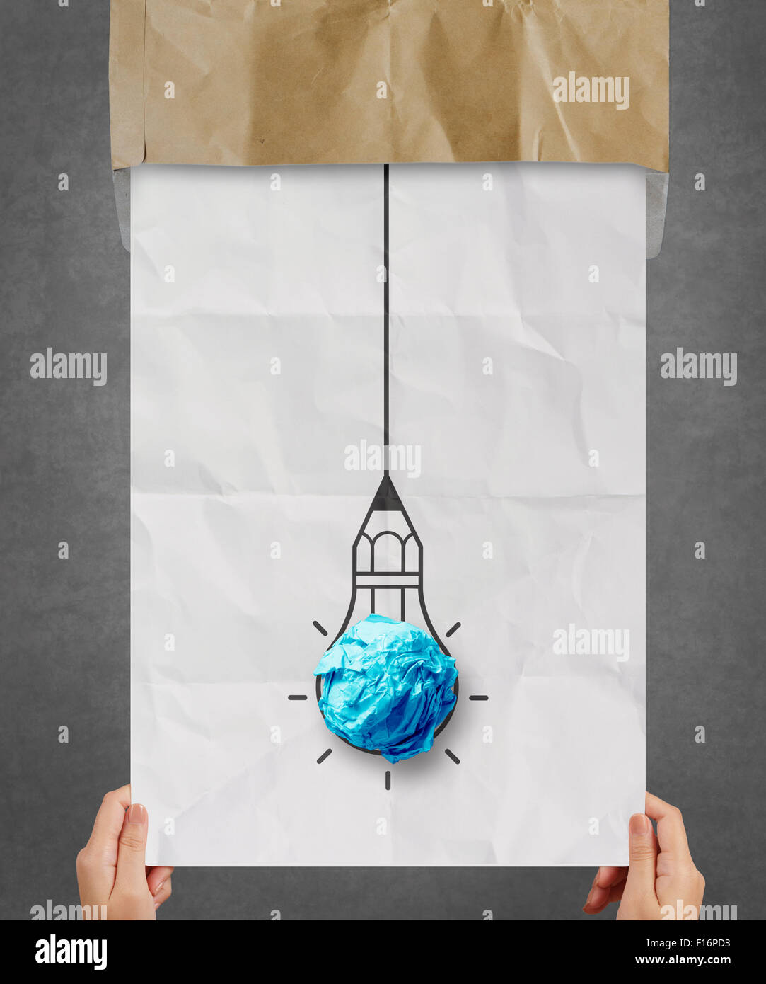 hand pulling light bulb crumpled paper out of recycle envelope as ...