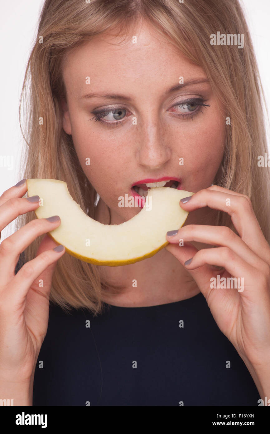Blonde woman biting into a slice of melon Stock Photo - Alamy