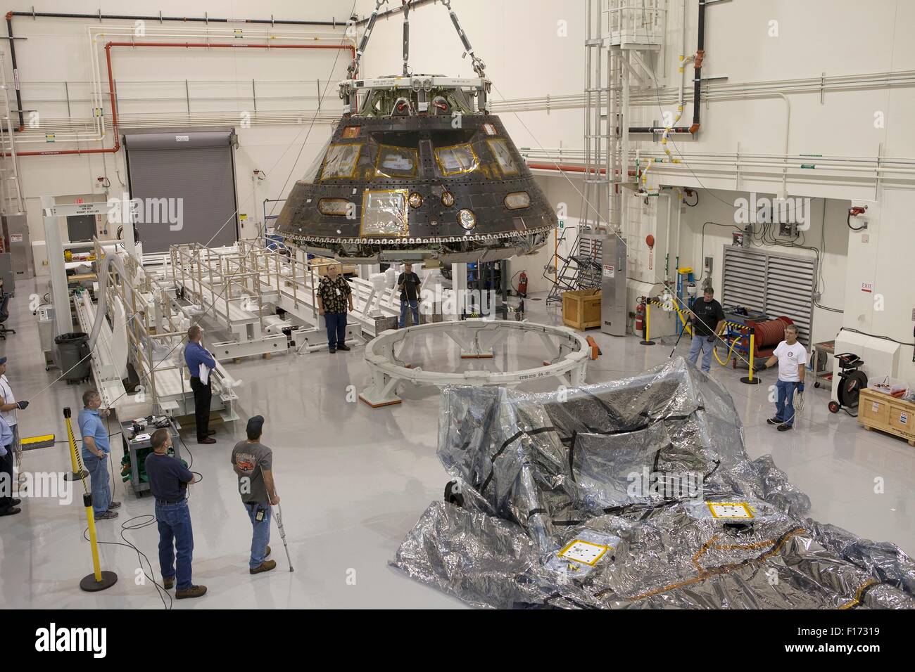 Workers lower the Orion spacecraft that flew on Exploration Flight Test ...