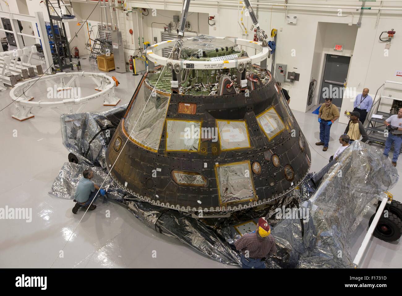 Workers lower the Orion spacecraft that flew on Exploration Flight Test ...