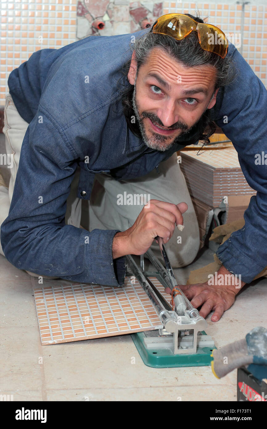 smiling tile worker cutting tiles in a bathroom Stock Photo - Alamy