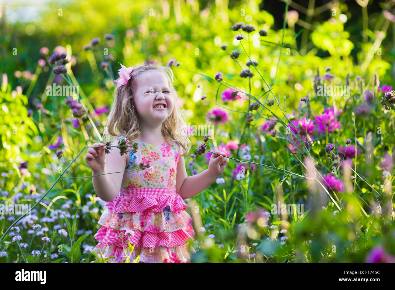 Little girl playing with flowers in the garden. Kids play outdoors in ...
